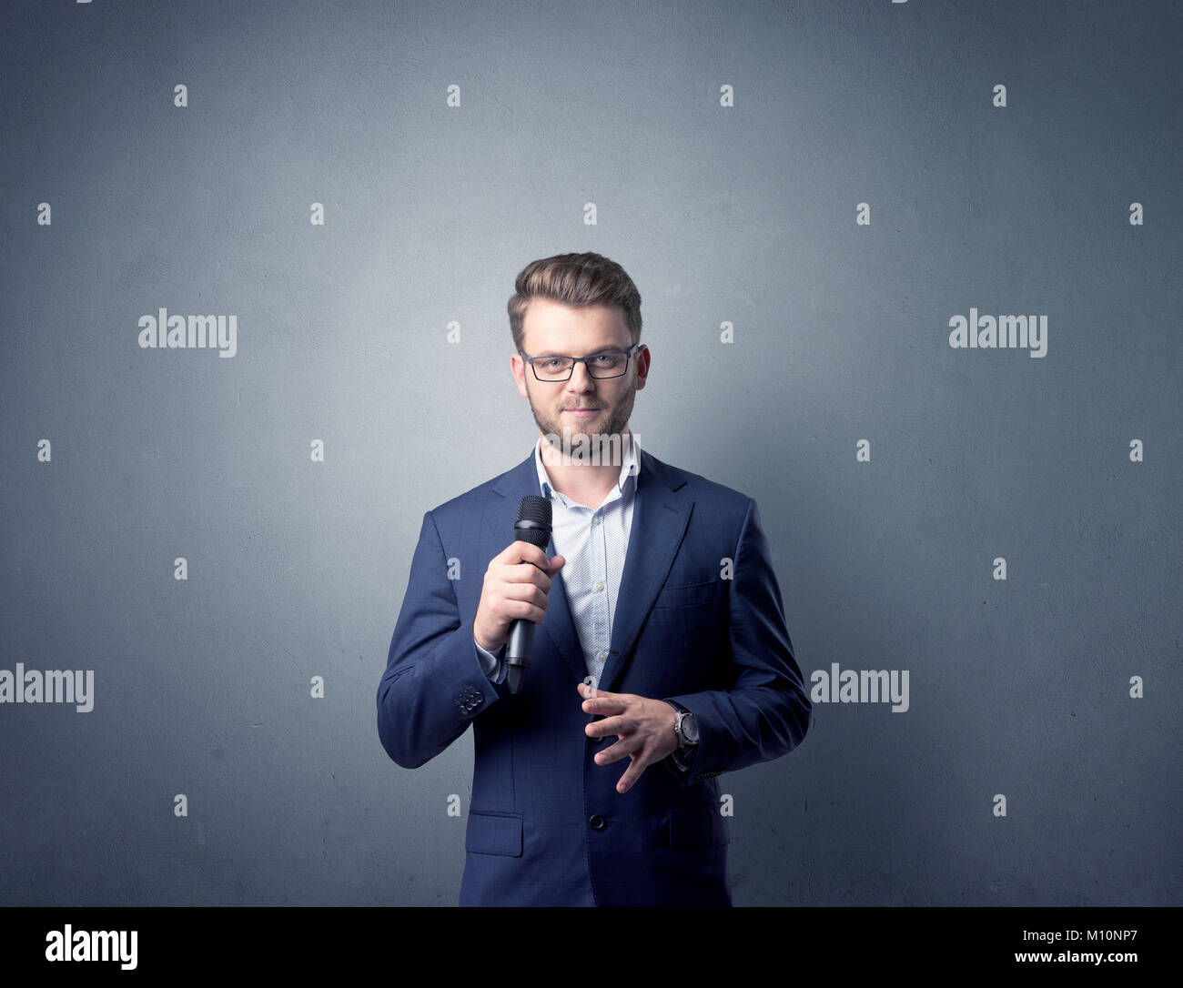 Businessman speaking into microphone with blue background Stock Photo ...