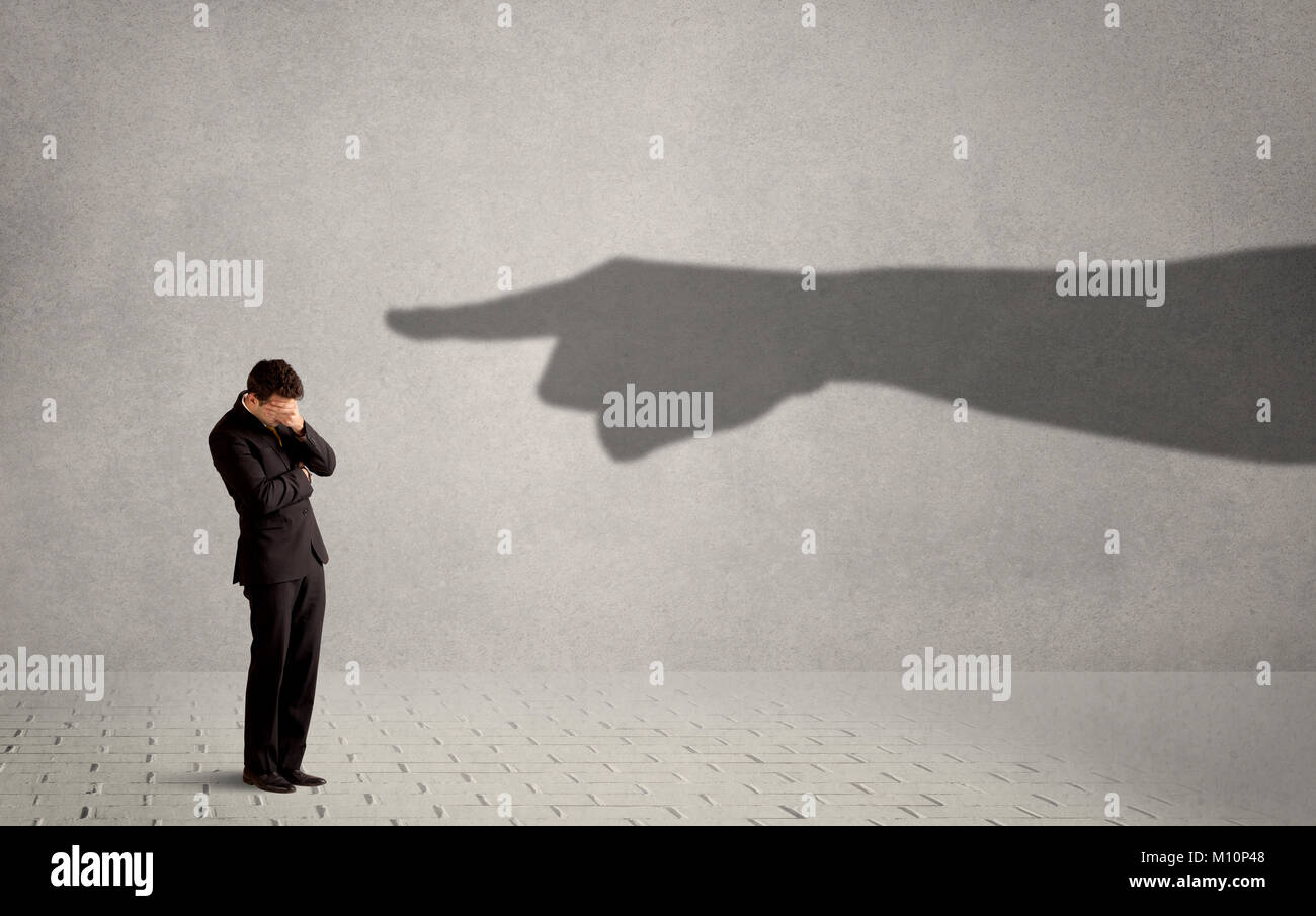 Business person looking at huge shadow hand pointing at him concept on ...