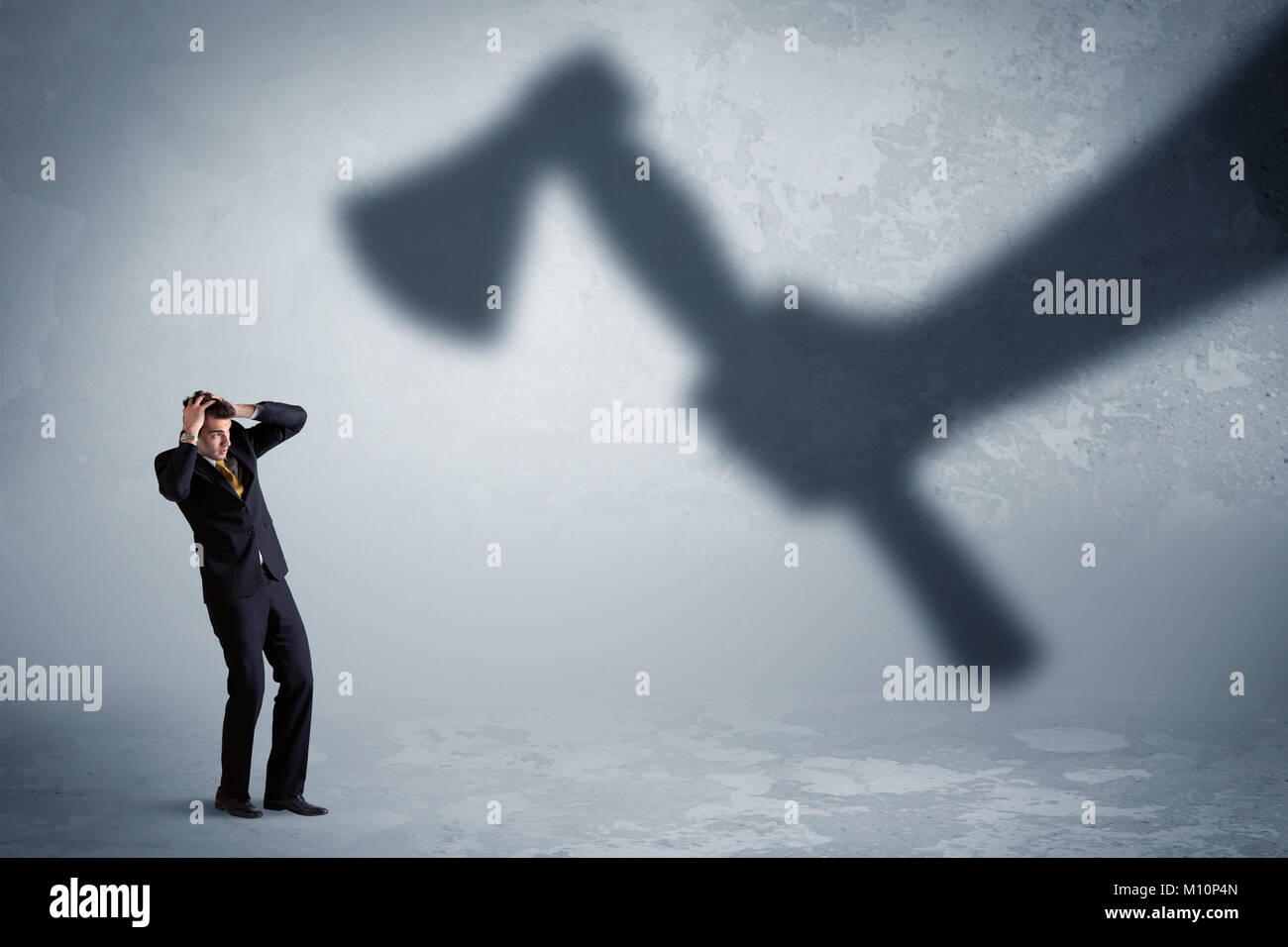 Businessman afraid of a huge shadow hand holding an axe concept on ...