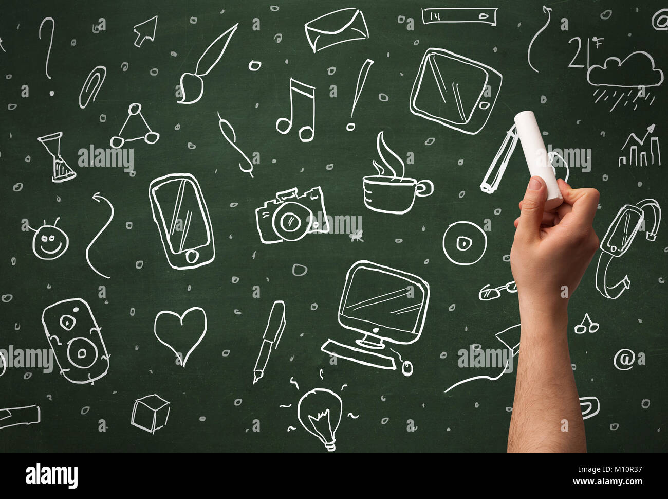 A person drawing media and communication icons on school blackboard ...