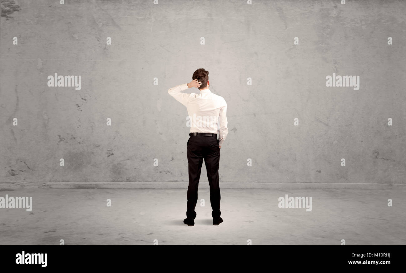 A confused sales person having a dilemma, standing with his back in ...