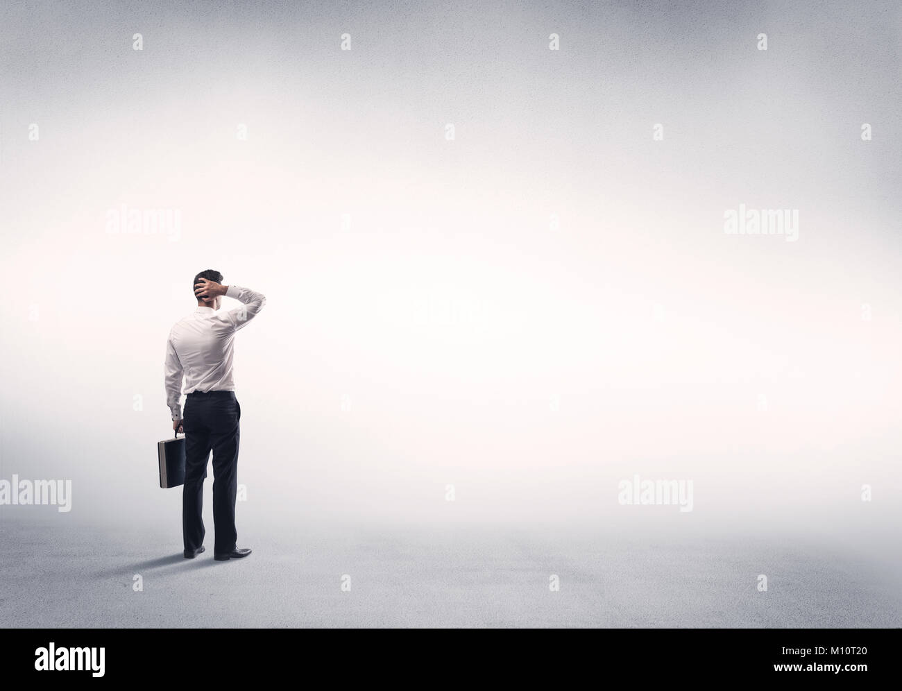 Corporate business male in modern suit standing in big blank empty grey ...