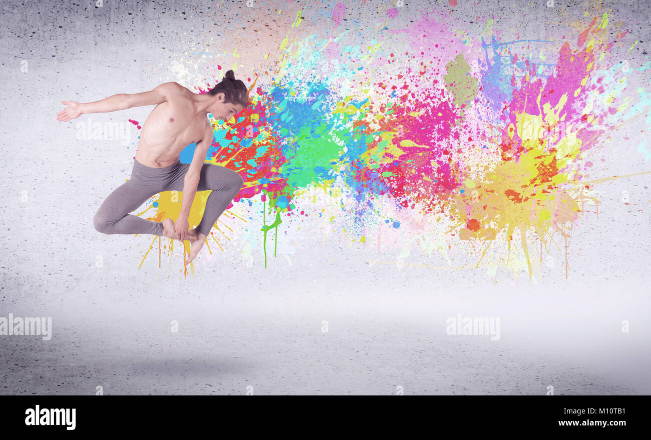 Modern street dancer jumping with colorful paint splashes on back wall ...