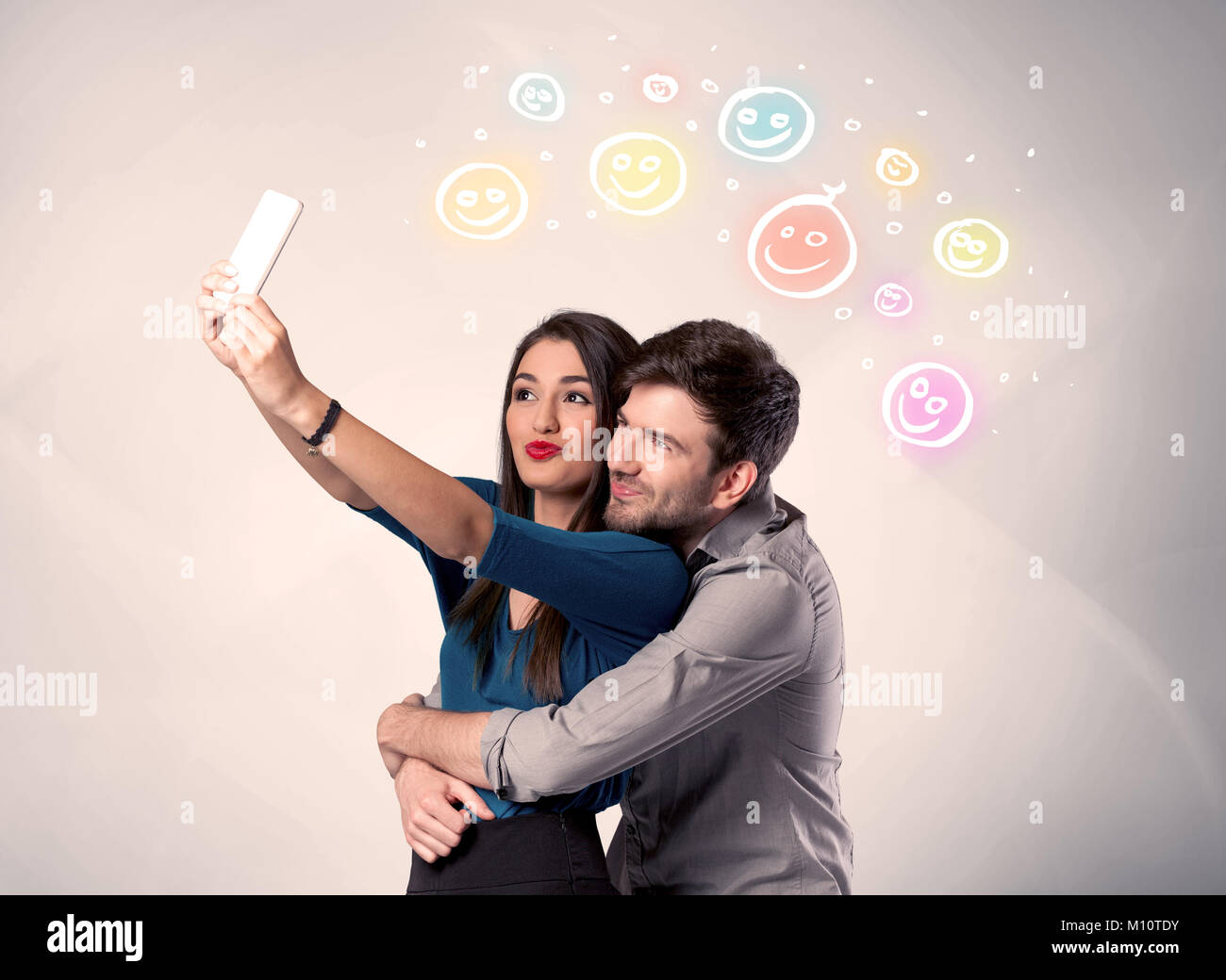 A cheerful young couple taking selfie photo with mobile phone and ...
