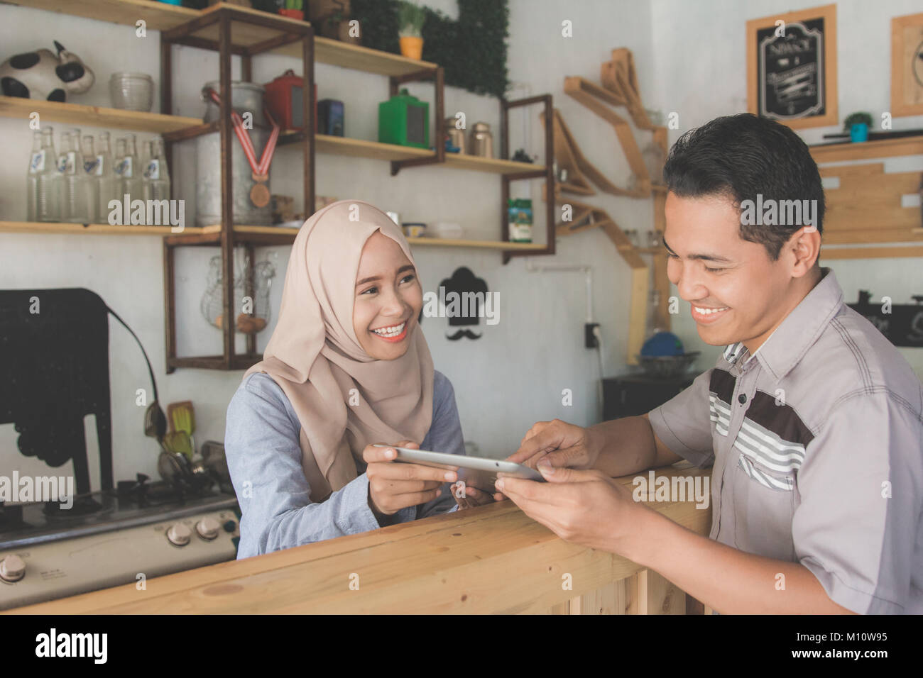 portrait of asian muslim female waitress showing cafe menu to her ...