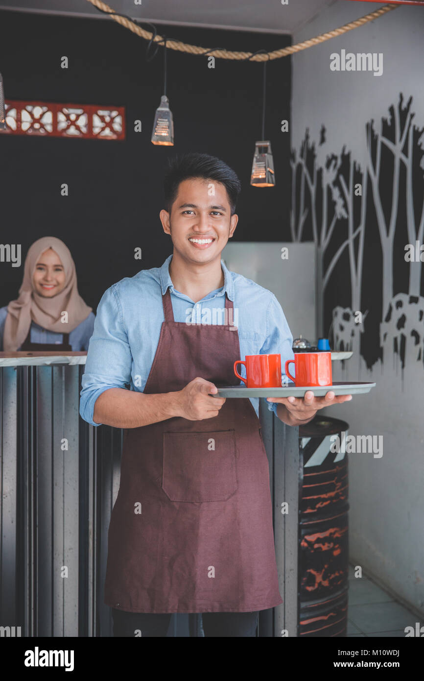 happy asian male cafe waiter holding tray with two cup of coffee ...