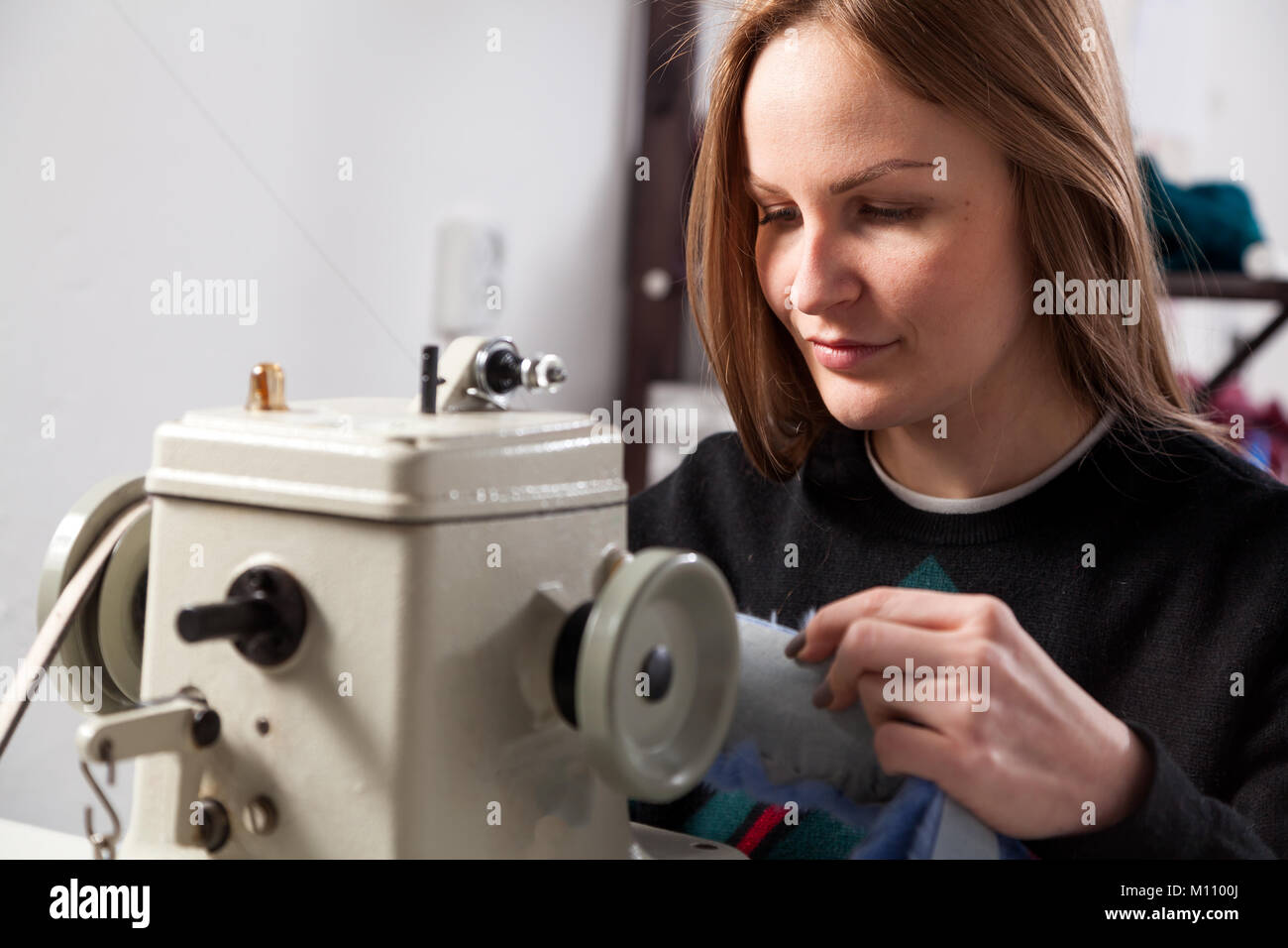 Sewing process of the female fur coat. Close up of a young cheerful ...