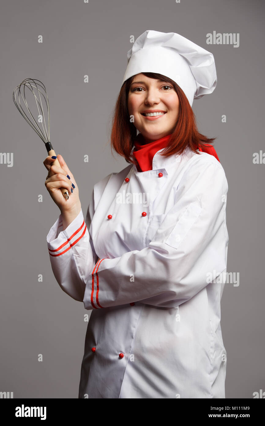 Image of woman cook in white robe and cap with whisk in hand on empty ...