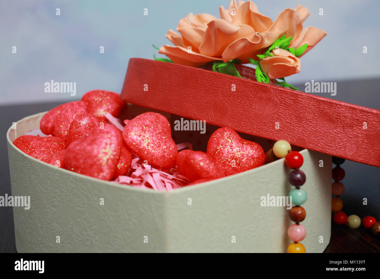 Ajar red box in the shape of a heart with a decorative flower, in a box ...