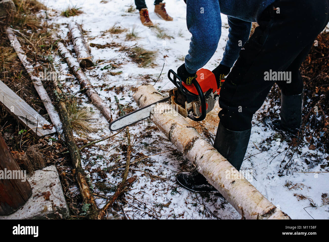 Process of sawing log by chainsaw in the winter Stock Photo - Alamy