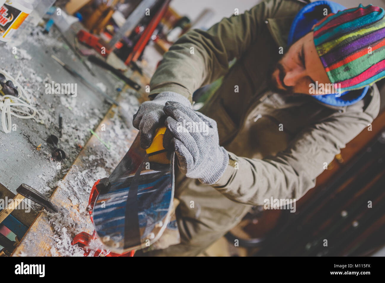 Male worker repairing Stone, edge sharpening in ski service workshop ...