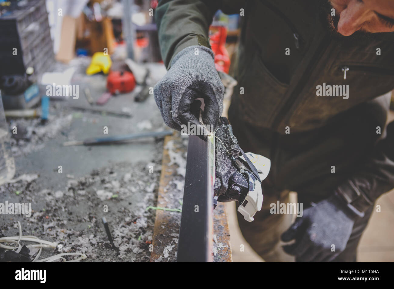 A man repairman in workshop ski service repairing the sliding surface ...
