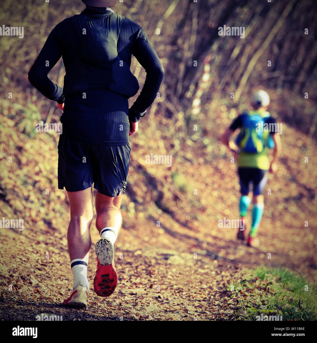 young athletes run in the path in the woods during a cross country race ...