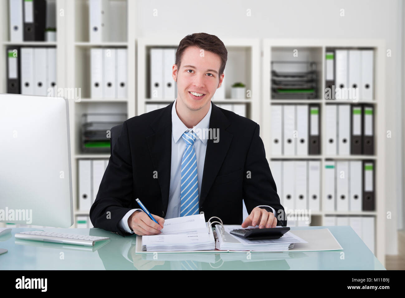 Portrait Of A Happy Young Accountant Calculating Invoice Stock Photo ...