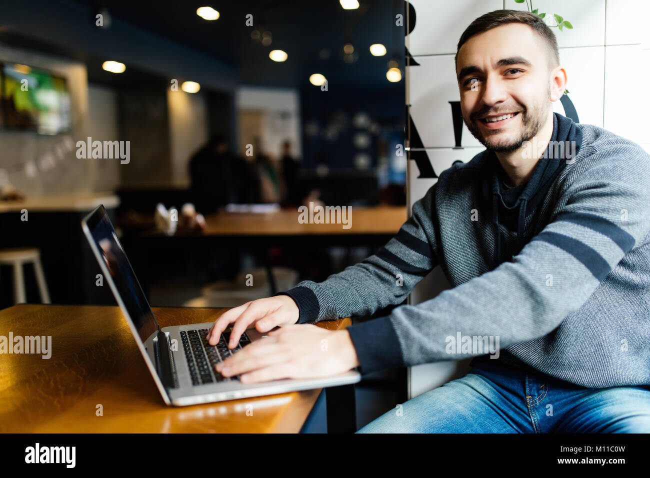 Young man sitting in cafe with laptop and coffee Stock Photo - Alamy