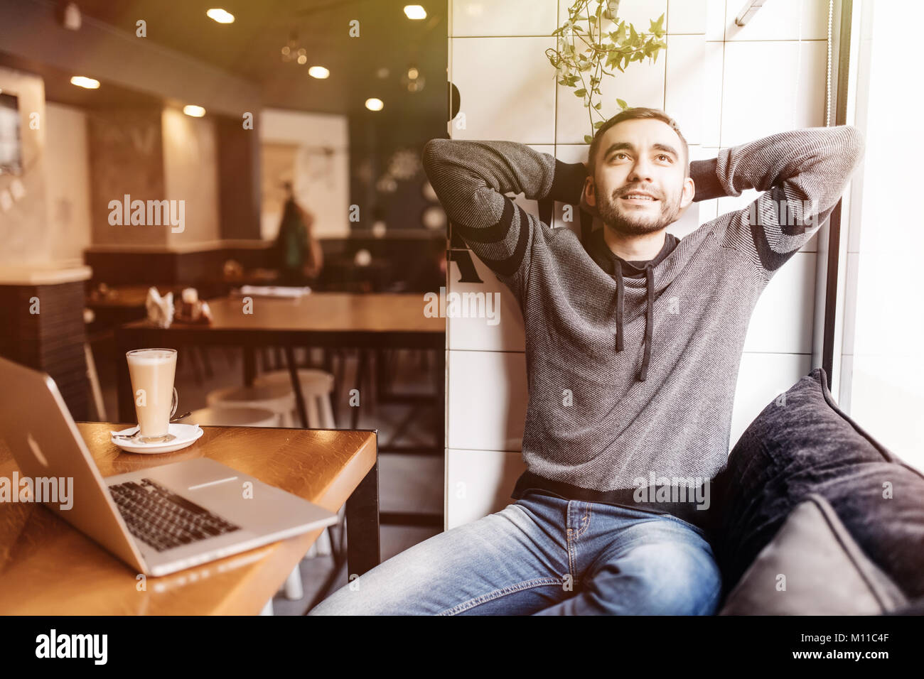 Young Man Relaxing at Window in Loft Cafe Stock Photo - Alamy