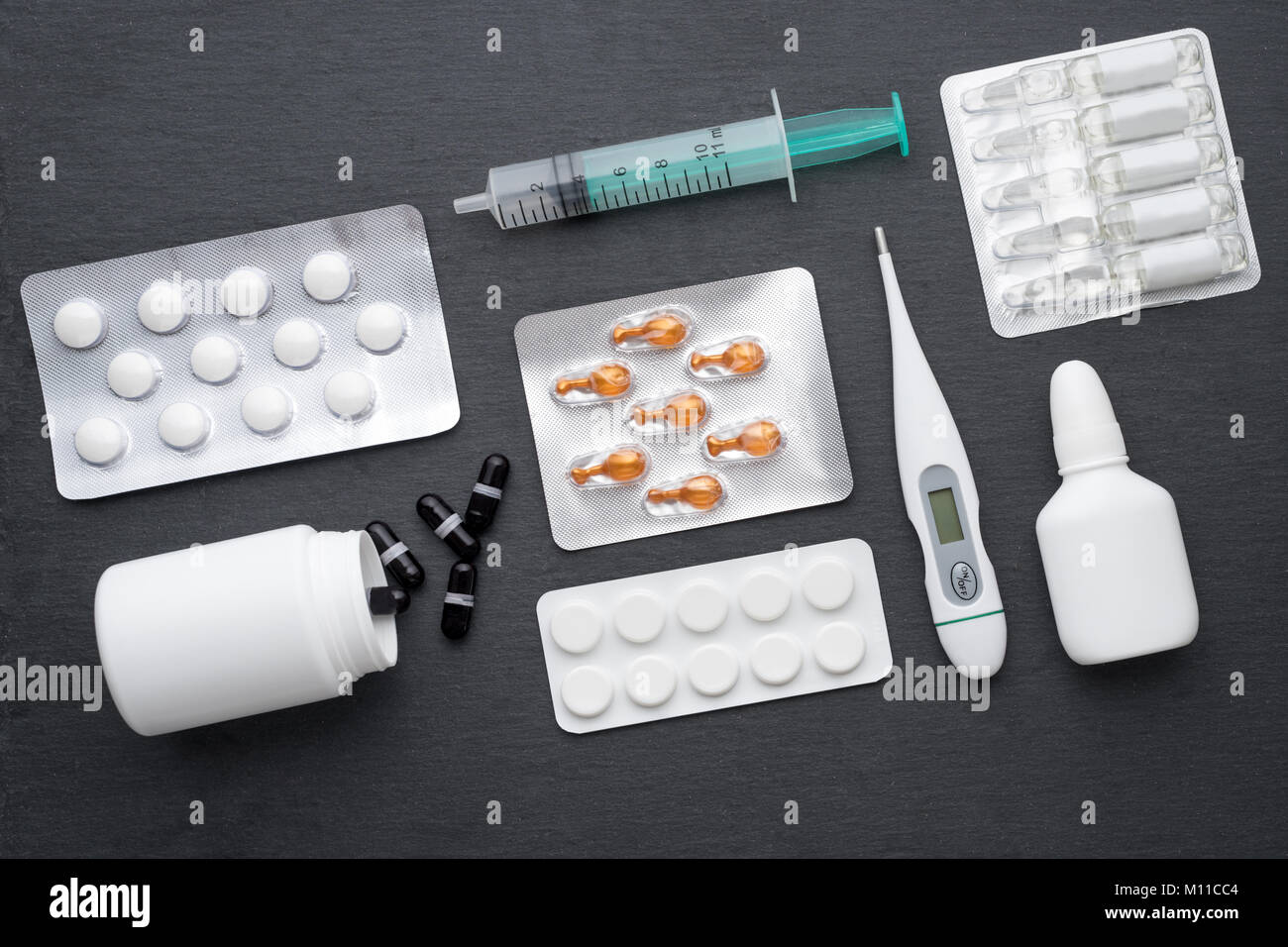 Thermometer, nasal drops tablets and ampoules with medicine on dark ...