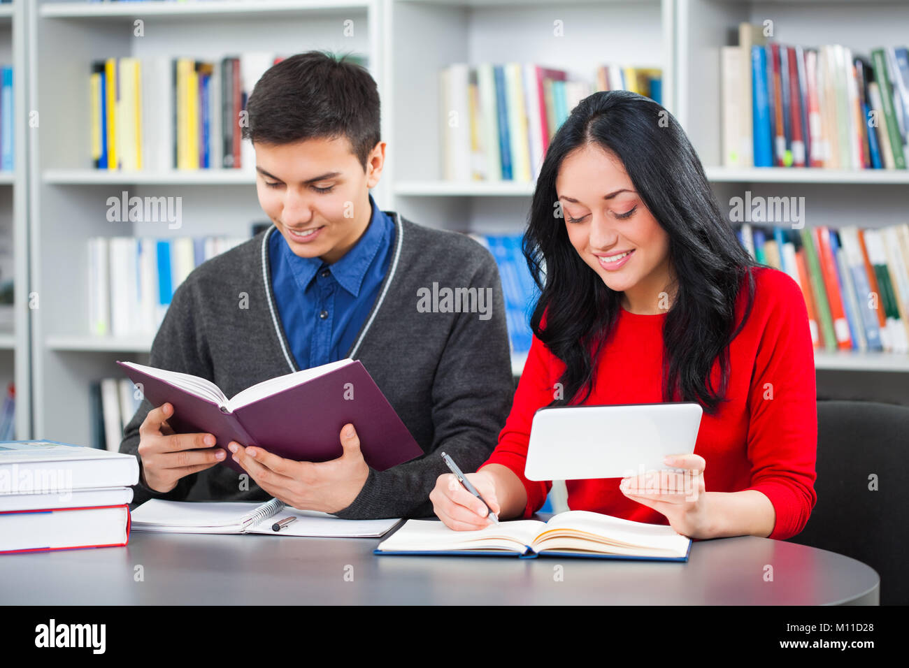 Happy students learning in library Stock Photo - Alamy