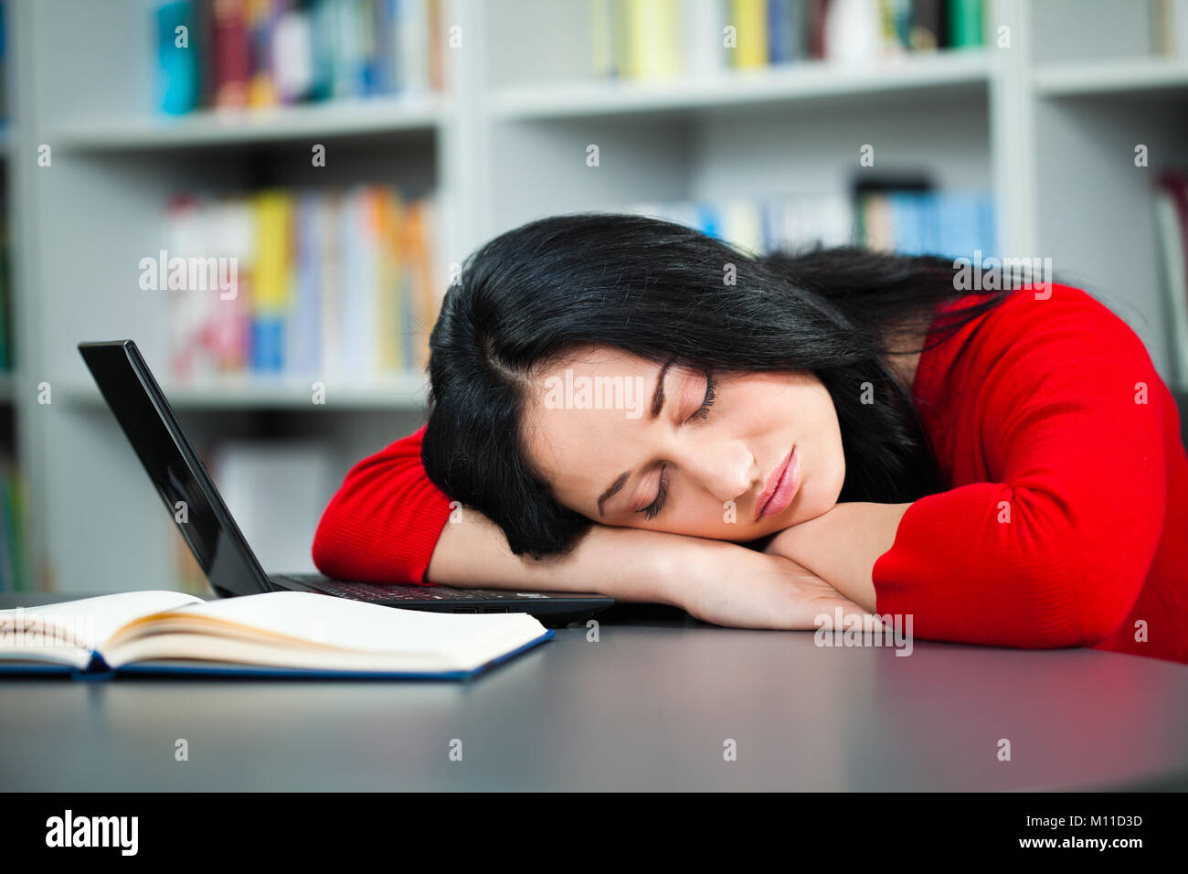 Tired student sleeping in library Stock Photo - Alamy