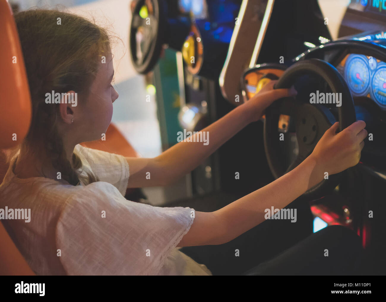 Little girl playing racing simulator game in theme park Stock Photo - Alamy
