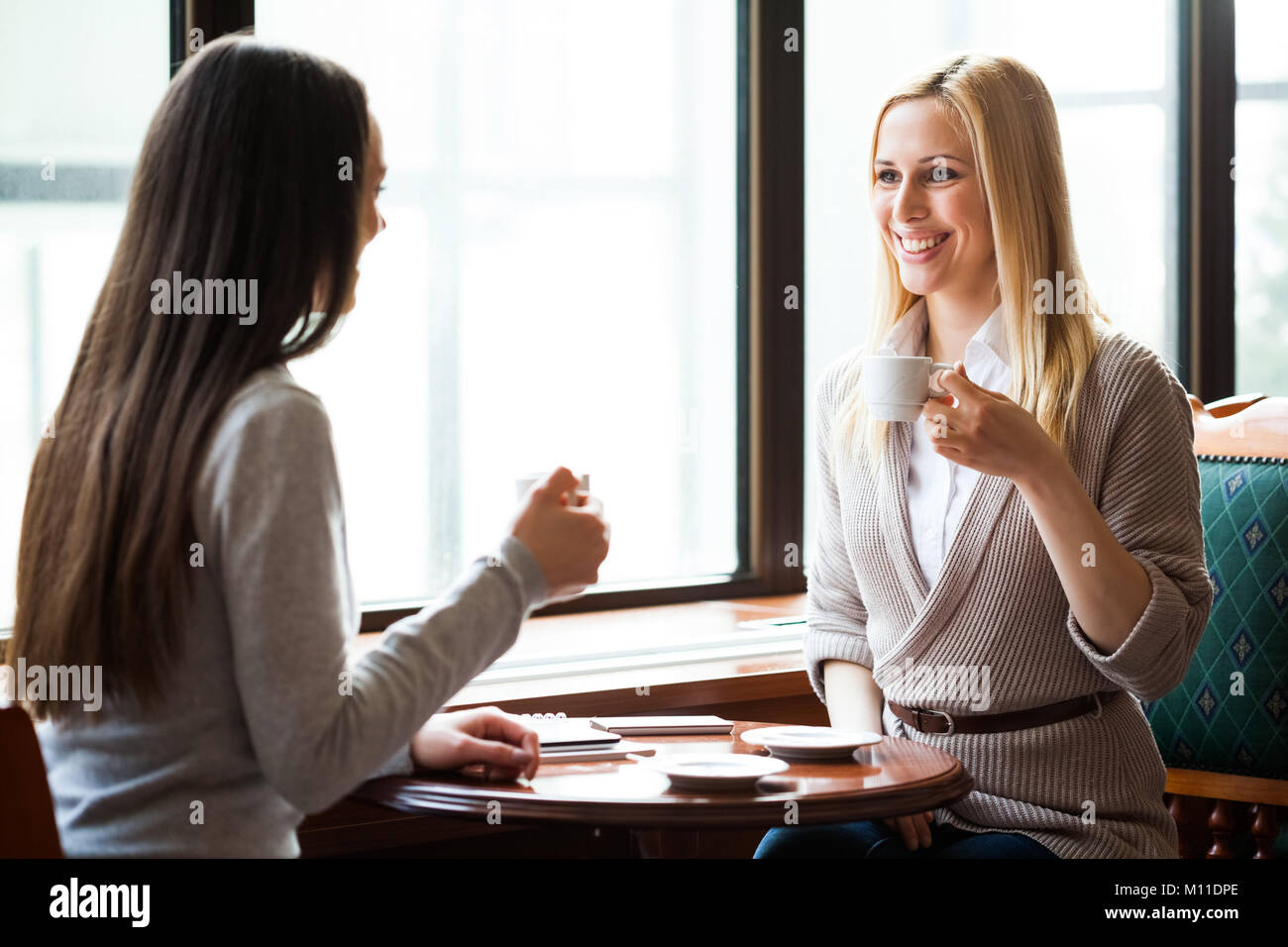 Two young women talking in cafe Stock Photo - Alamy