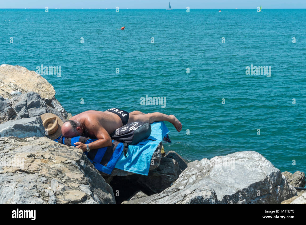 Man sunbathing on the rocks at Viareggio beach, Tuscany, Italy Stock ...