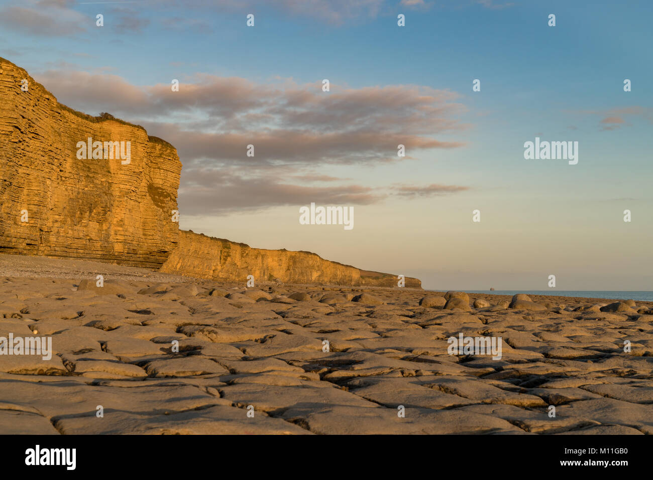 The stones and cliffs of Llantwit Major Beach in the evening sun with ...