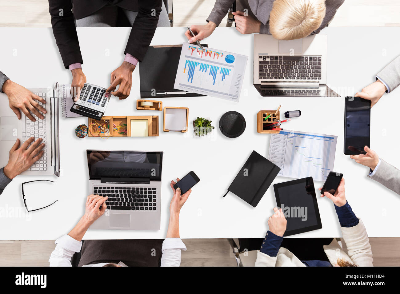 Businesspeople Using Electronic Device While Working On Graph In Office ...