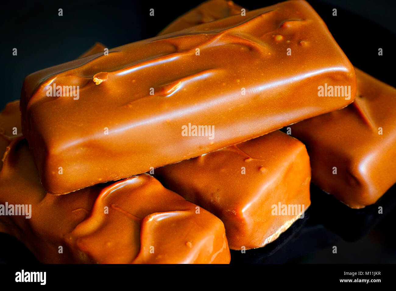 Four chocolate bars in heap. Black background Stock Photo - Alamy