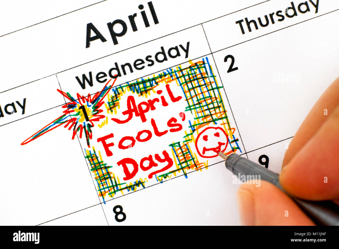 Woman fingers with pen writing reminder April Fools Day in calendar ...