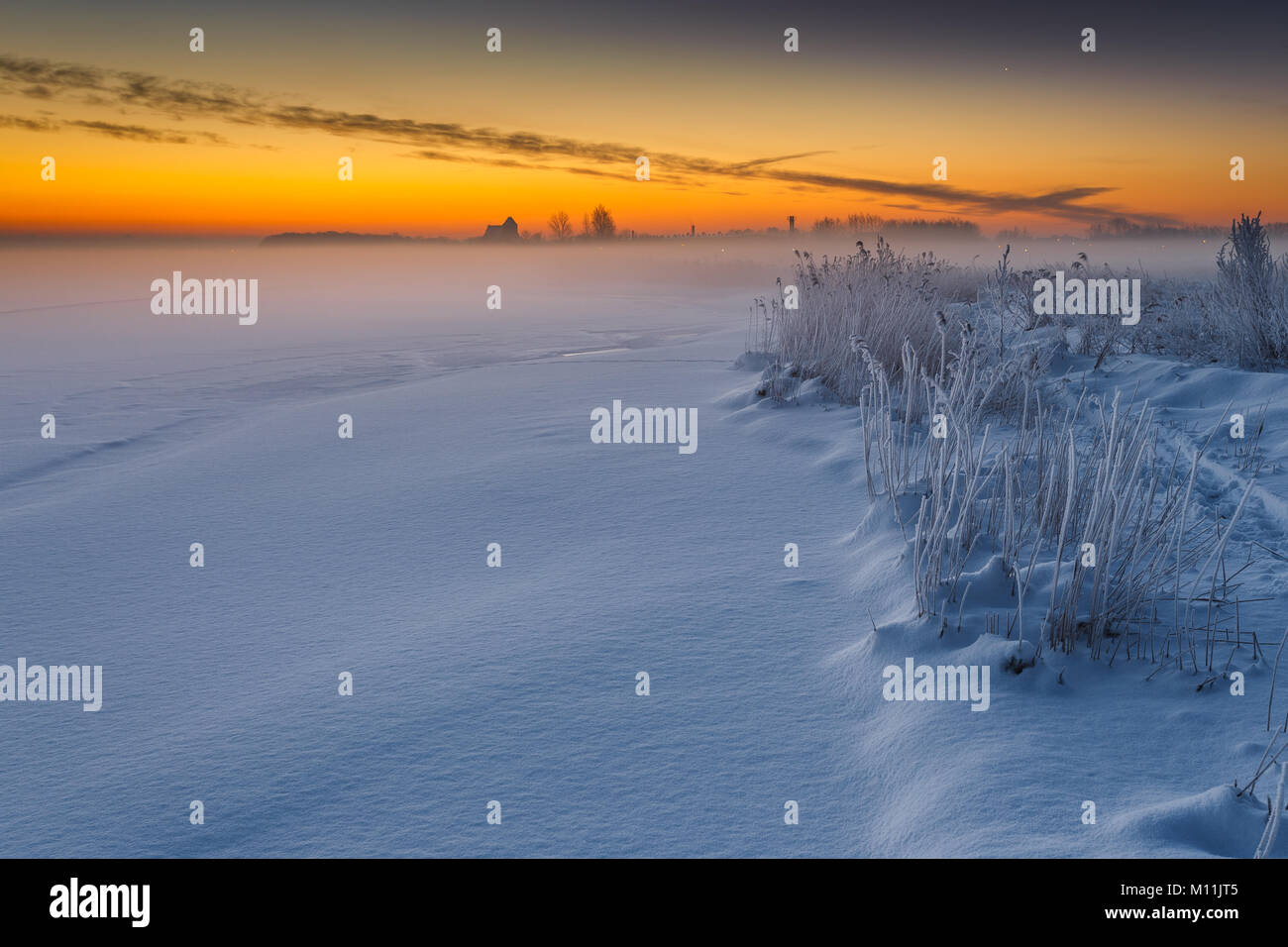 Winter landscape at frozen bay of Puck. Warm light of sunrise early ...