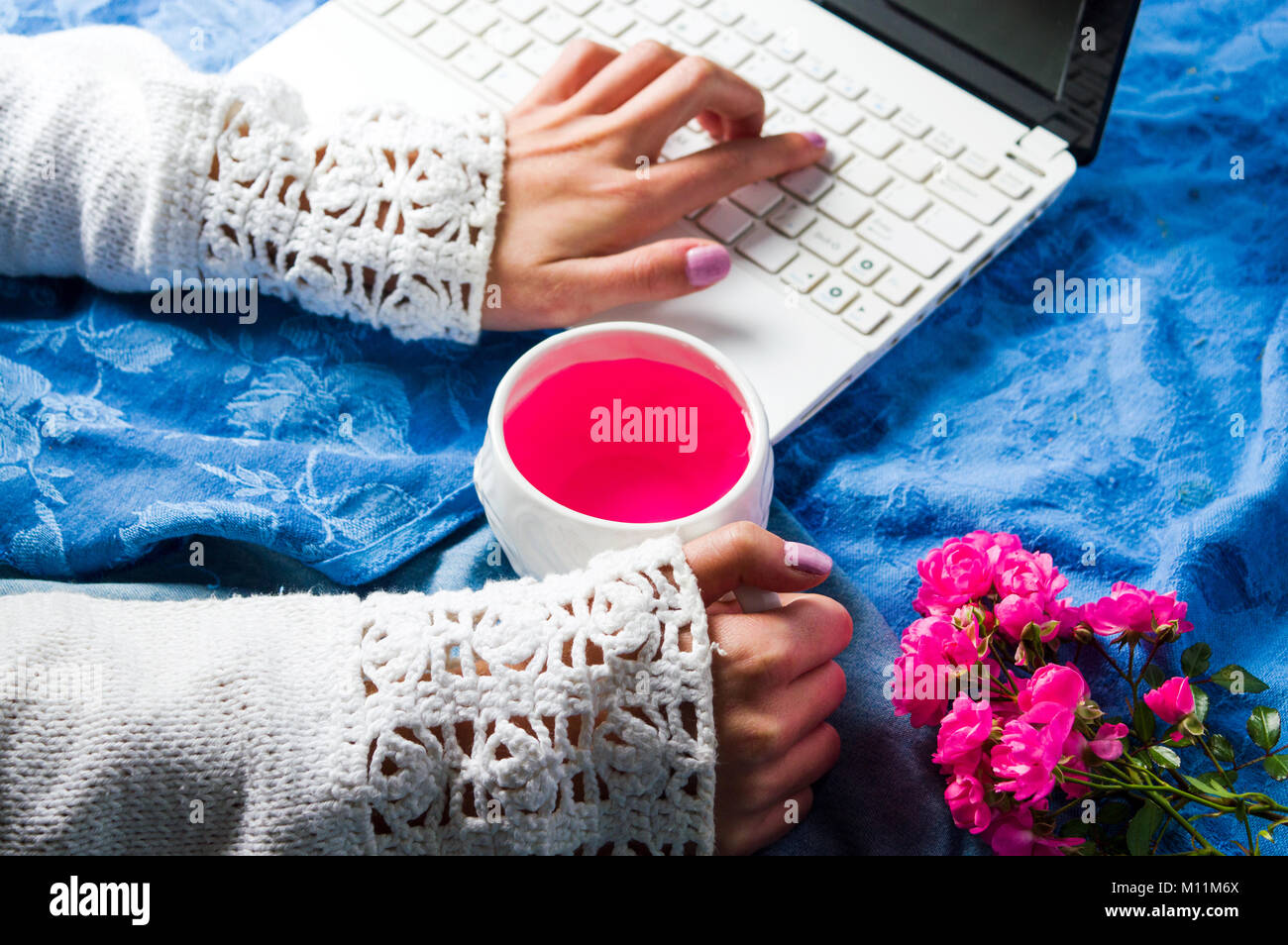 Girl having a cup of tea while working on laptop Stock Photo - Alamy