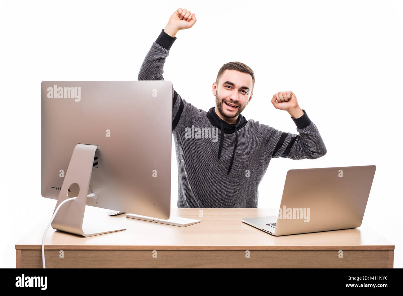 Young man with raised fists using laptop and pc Stock Photo - Alamy