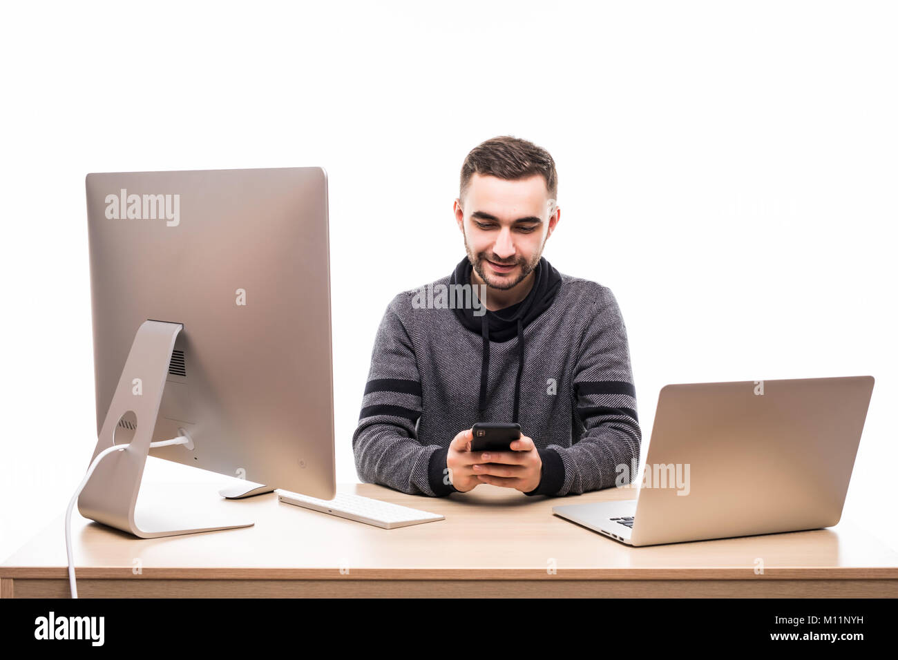 Smiling businessman sitting behind his desk with laptop and pc and ...