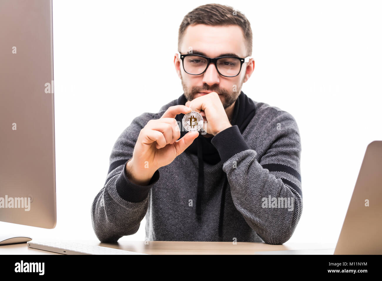 Handsome man thinking over bitcoin at working table with laptop and ...
