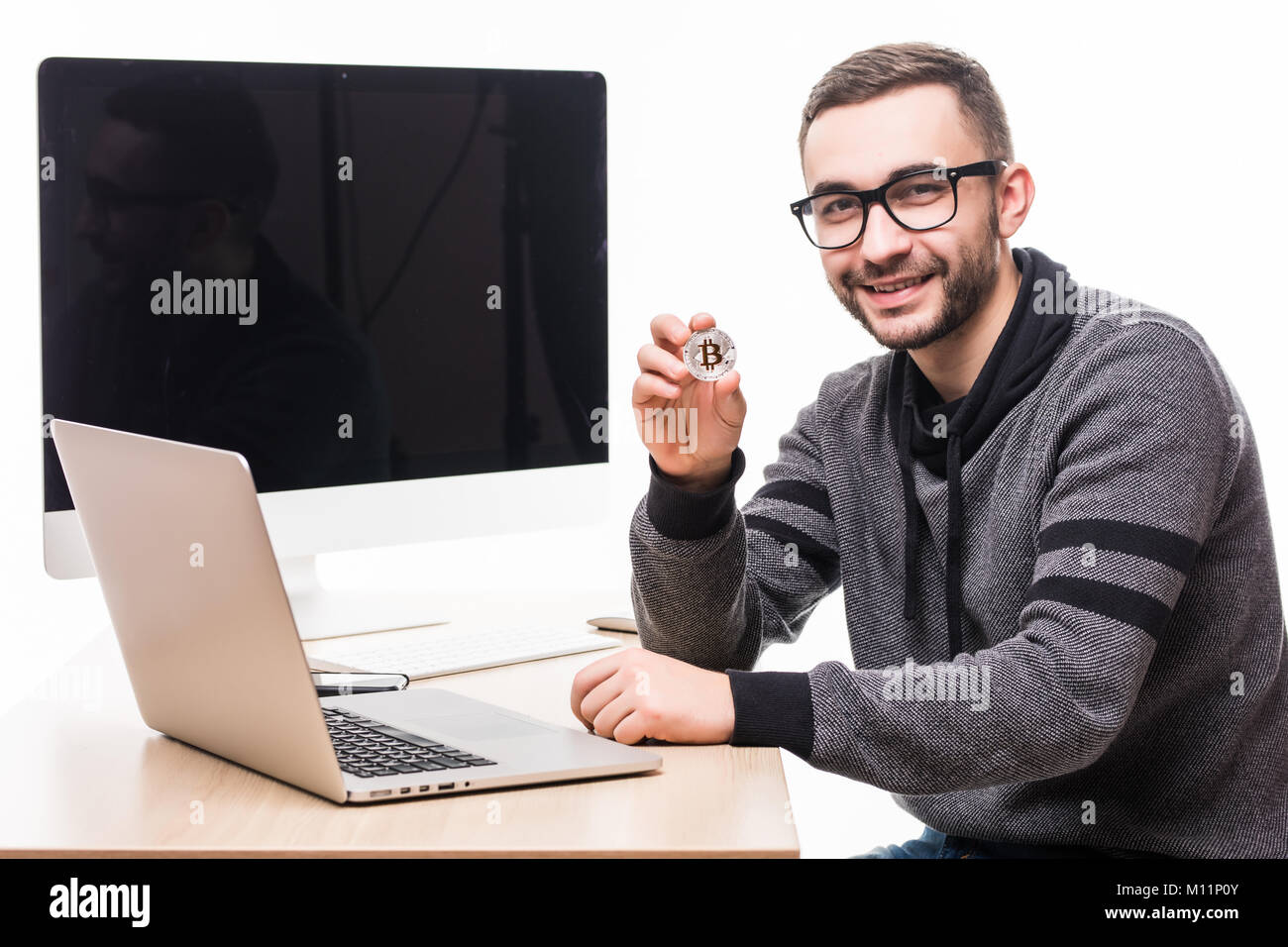 Handsome man sitting at office place with laptop and screen of monitor ...