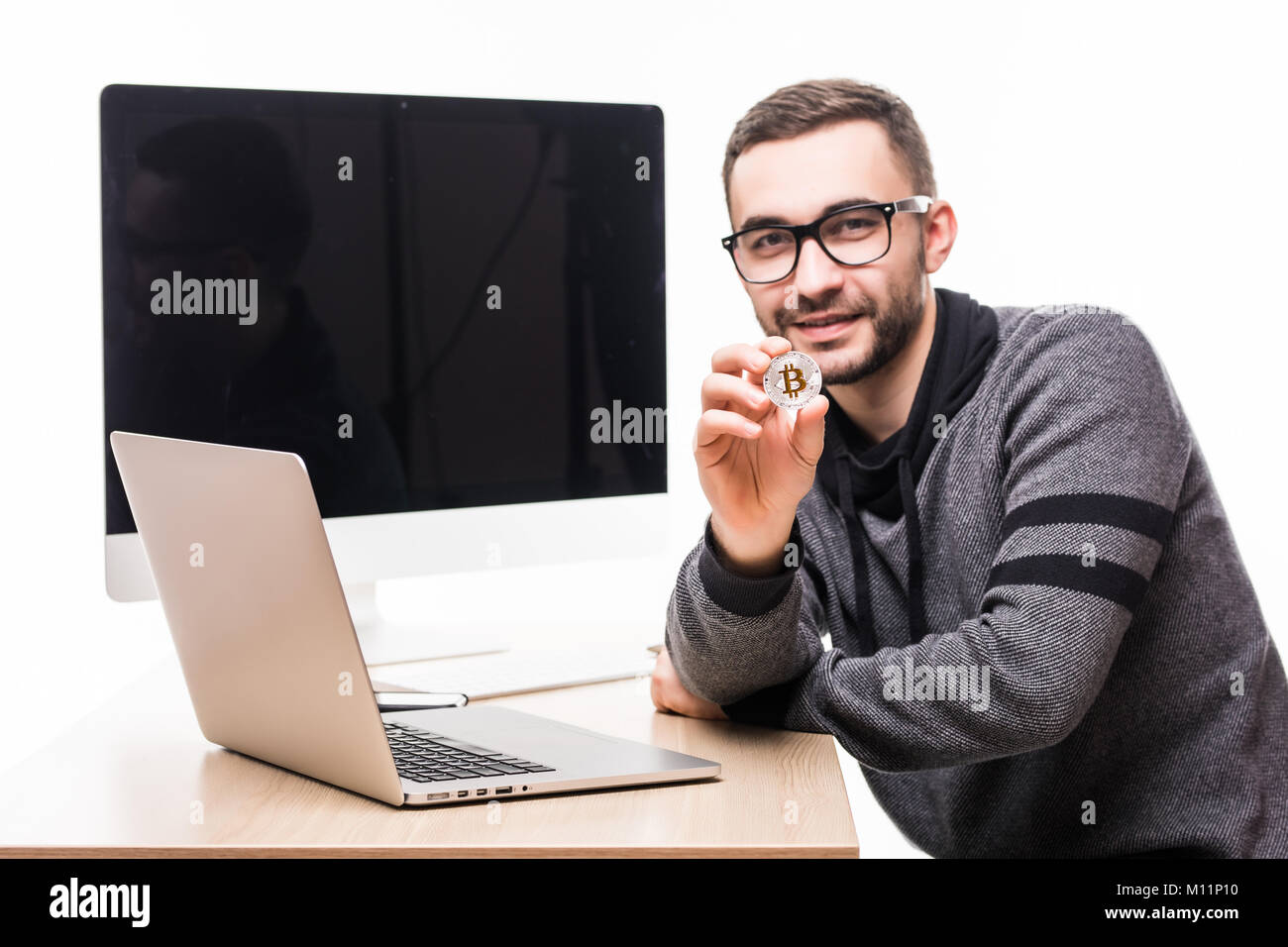 Handsome man sitting at office place with laptop and screen of monitor ...