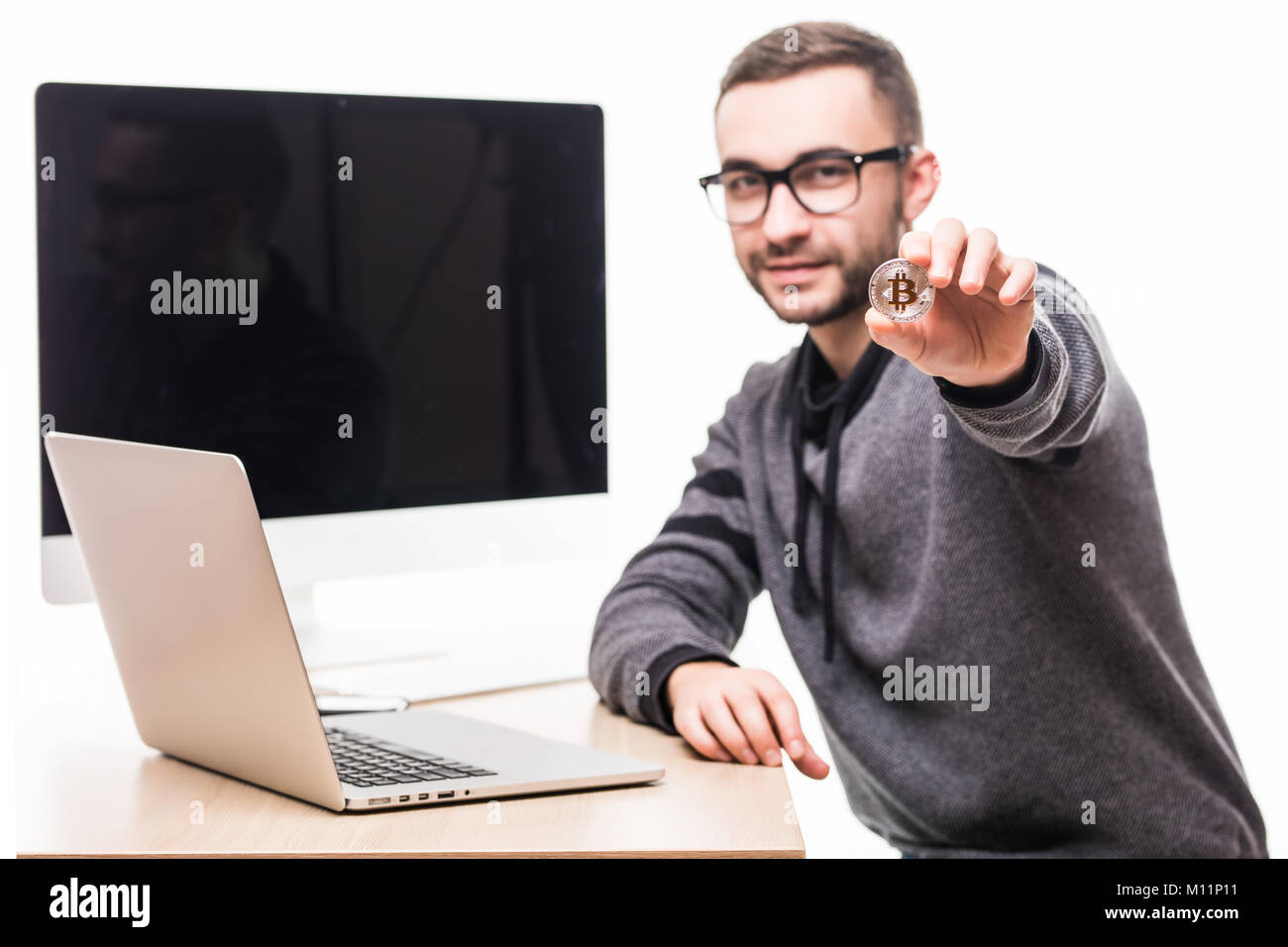Handsome man sitting at office place with laptop and screen of monitor ...