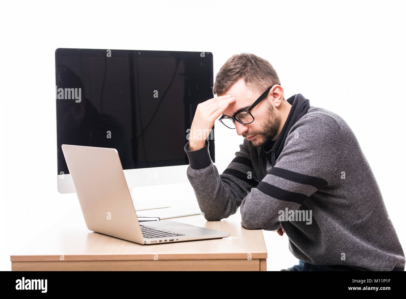 Sad handsome man in glasses working on laptop with screen of monitor on ...