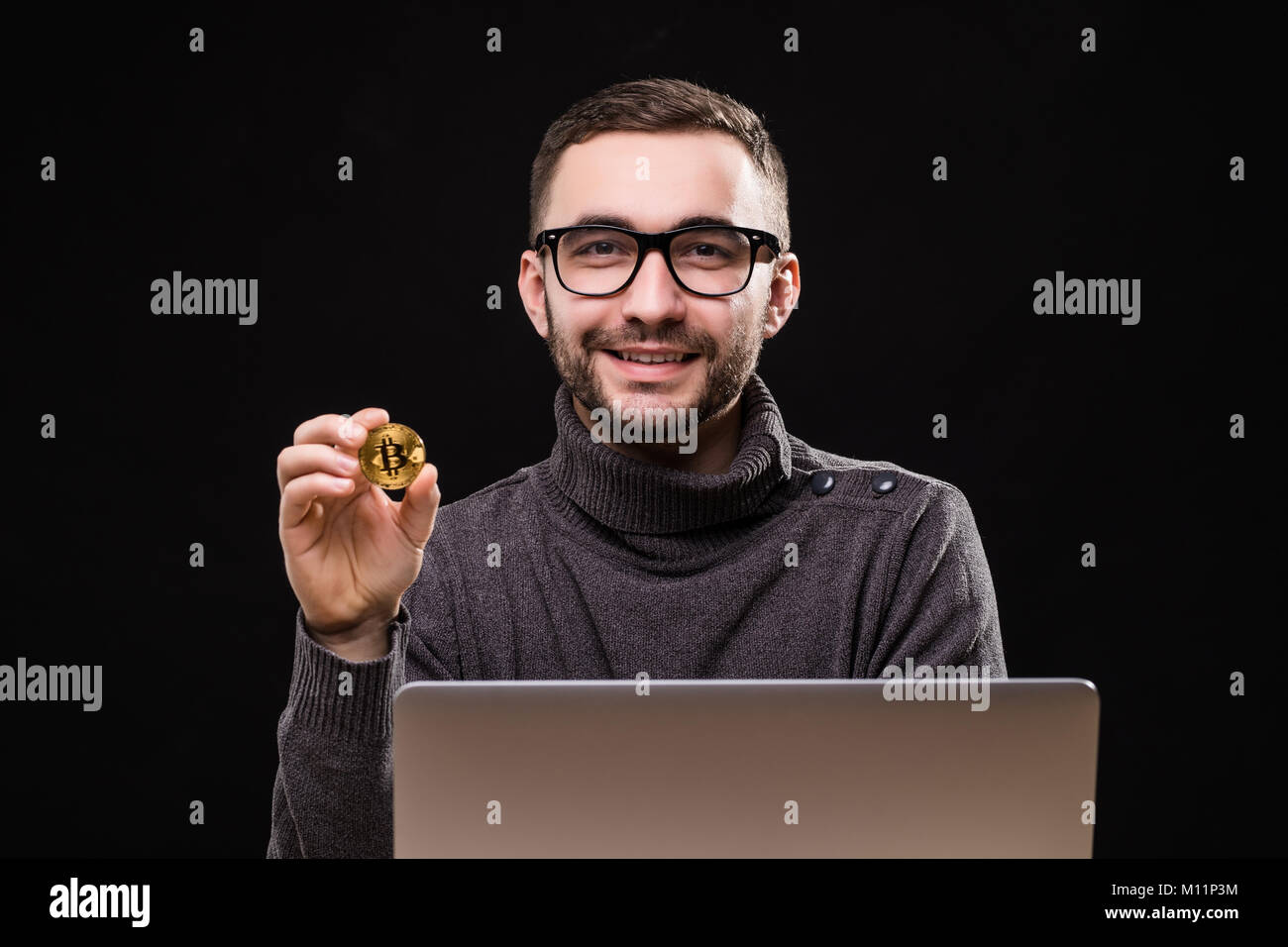 Portrait of a happy businessman showing bitcoin while sitting at desk ...
