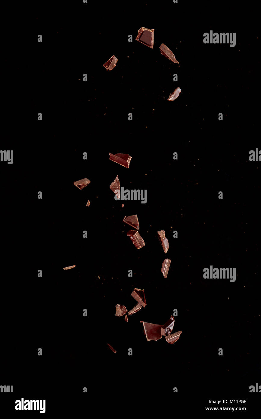 Chocolate chunks falling on a black background. Action food photography ...