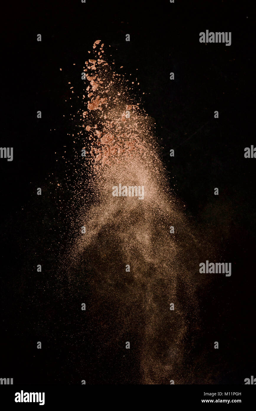 Cocoa powder explosion in motion. Chocolate dust on a black background ...