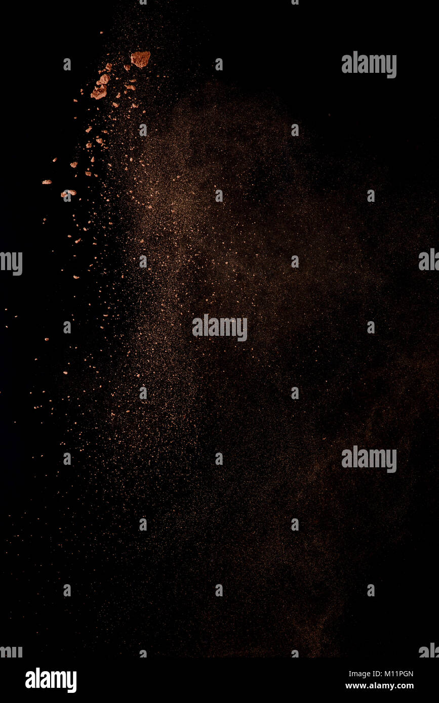 Cocoa powder explosion in motion. Chocolate dust on a black background ...