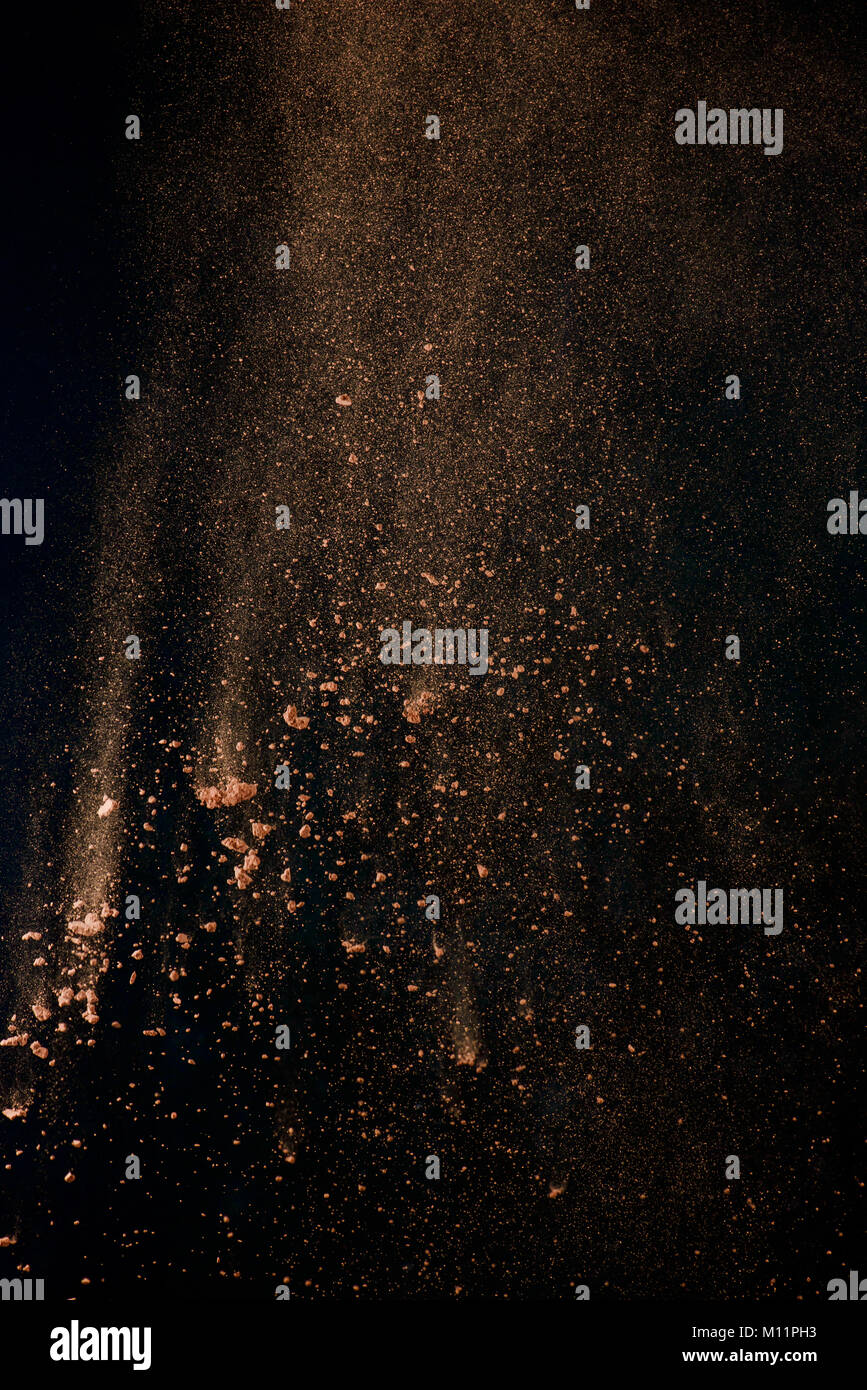 Cocoa powder explosion in motion. Chocolate dust on a black background ...