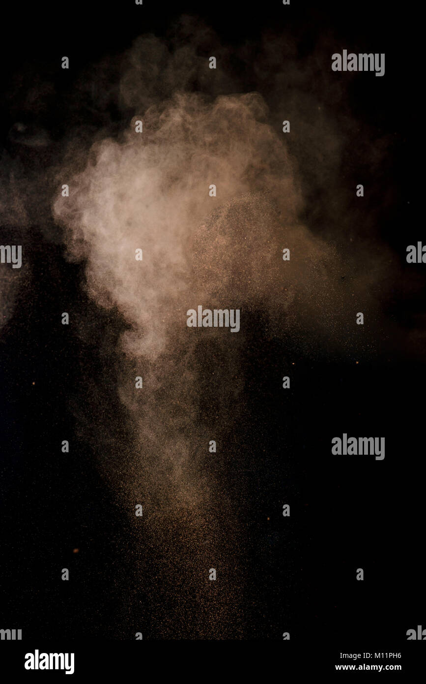 Cocoa powder explosion in motion. Chocolate dust on a black background ...