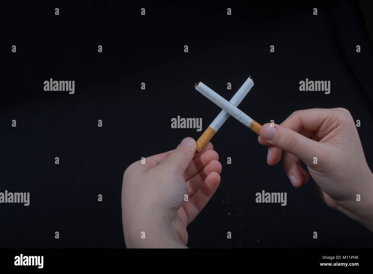 Hand is holding crossed cigarettes on black background Stock Photo - Alamy