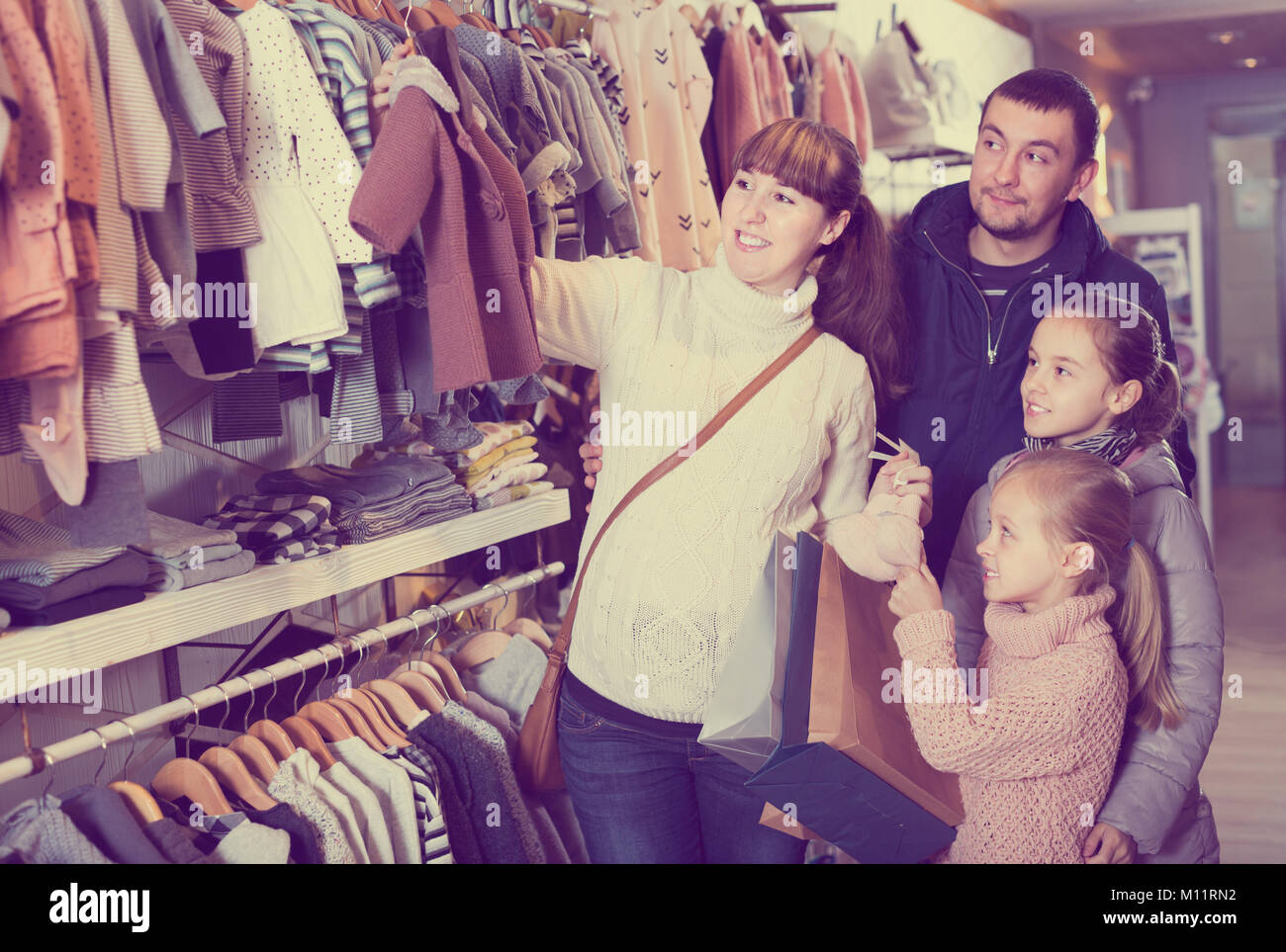 Young family with children searching clothes for new baby in children’s ...