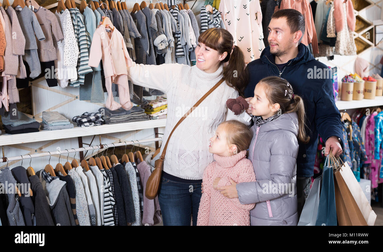 Happy family with children choosing clothes for newborn in children’s ...