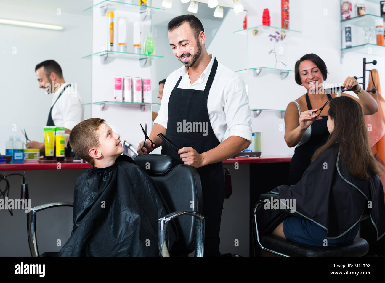Cute boy in elementary school age getting hairdo of man hairdresser in ...