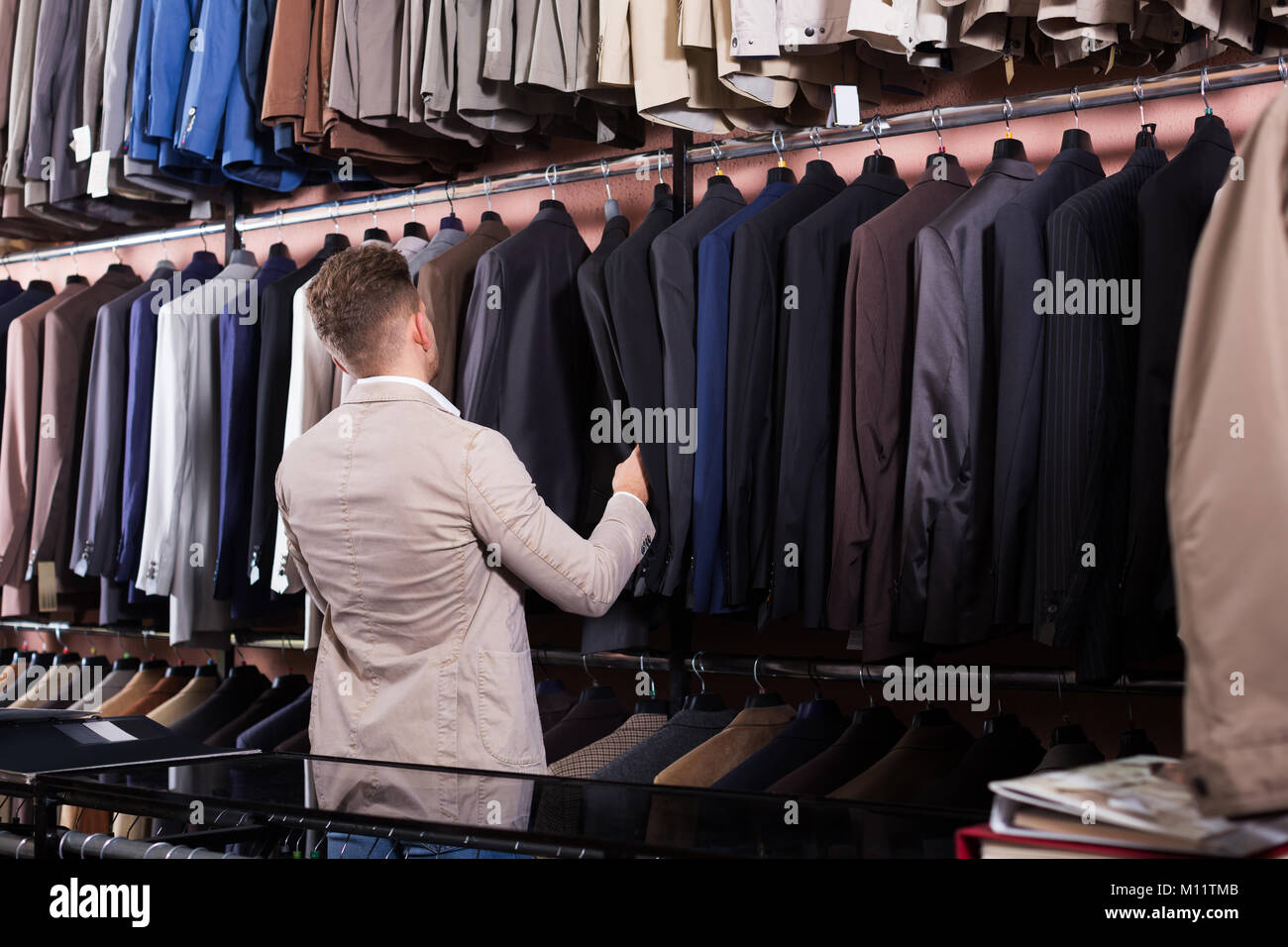 Positive guy deciding on new suit in men’s cloths store Stock Photo - Alamy